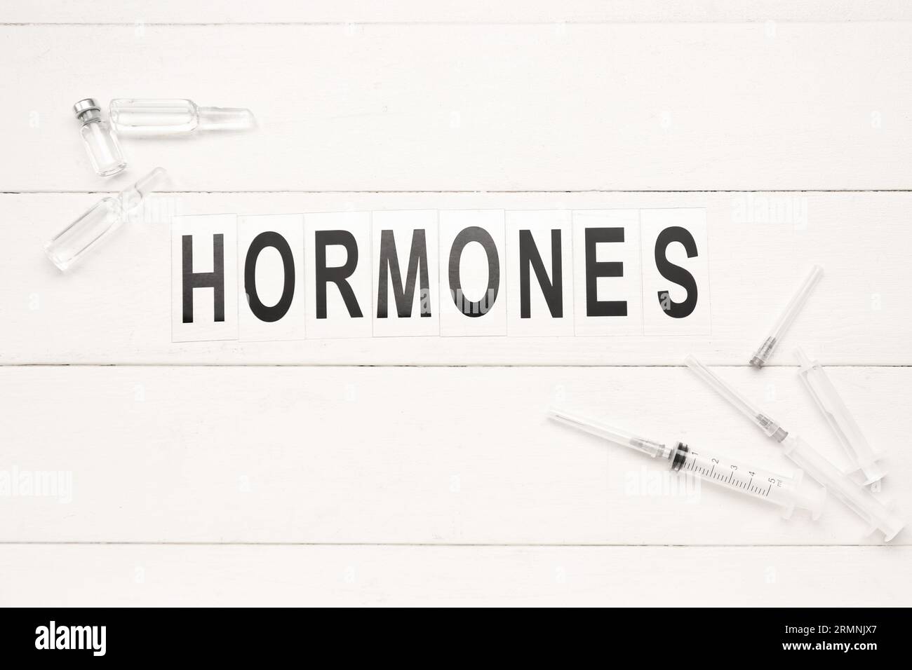 Word HORMONES with syringes and ampules on white wooden background ...