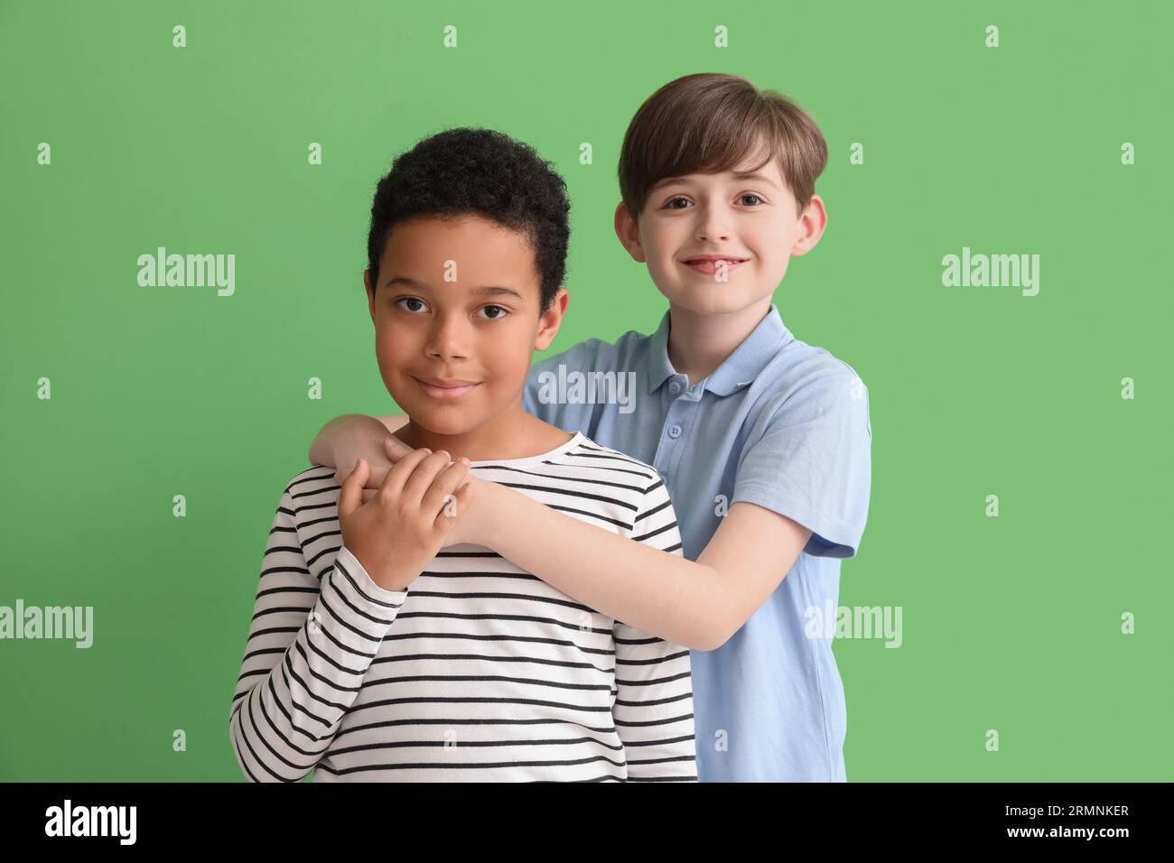 Cute little boys hugging on green background Stock Photo - Alamy