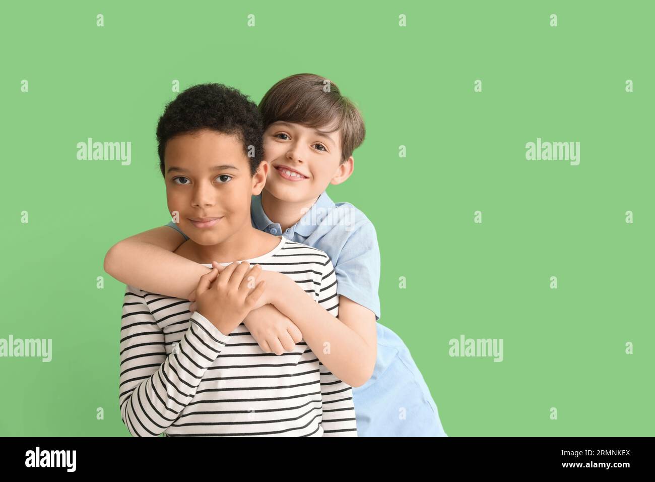 Cute little boys hugging on green background Stock Photo - Alamy