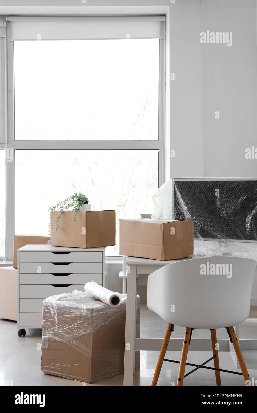 Interior of light office with cardboard boxes and stretch film on ...