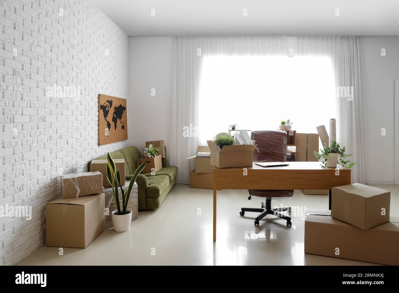 Modern workplace and sofa with cardboard boxes in office on moving day ...