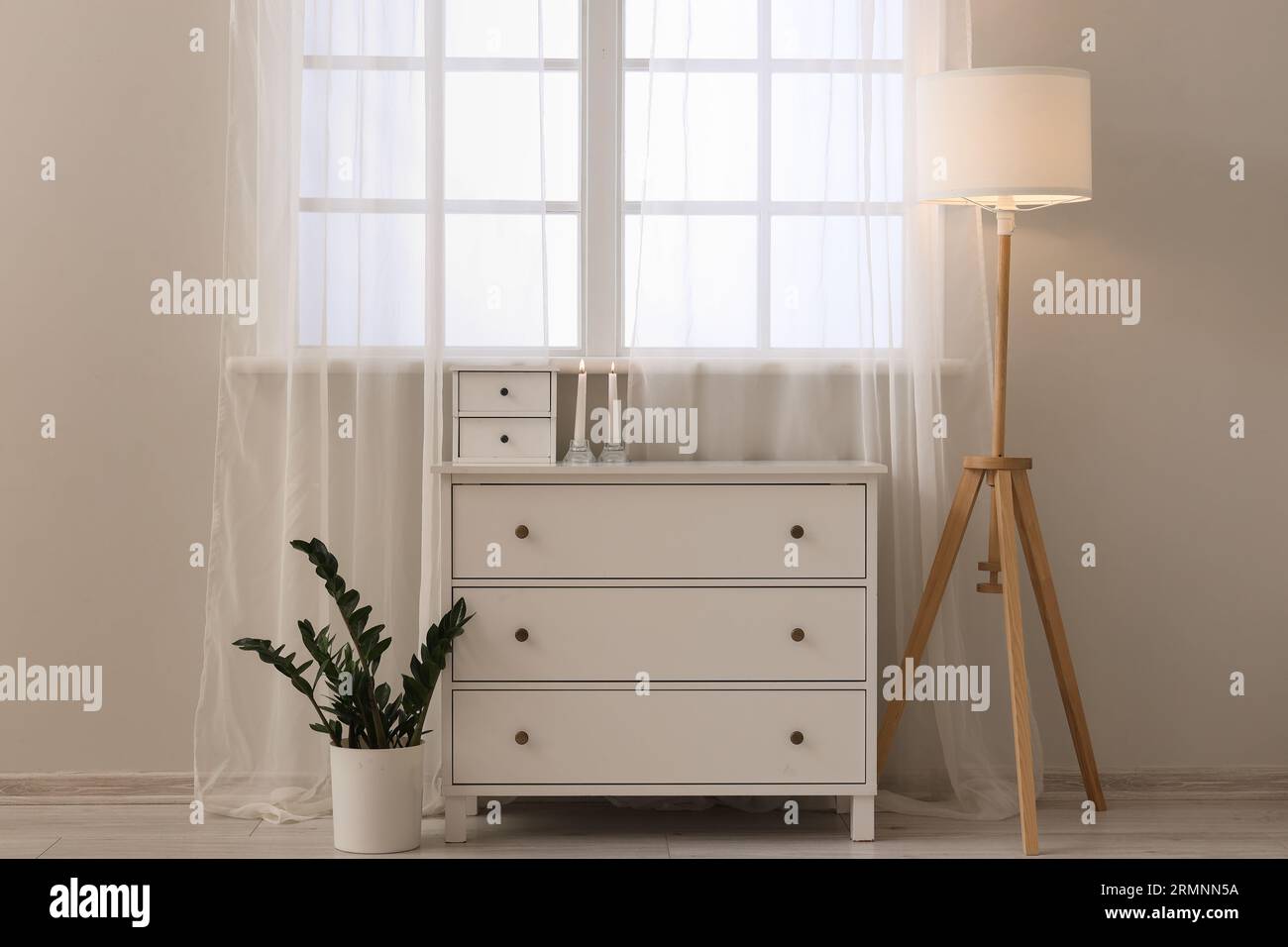 Interior of light room with drawers, lamp and window Stock Photo - Alamy