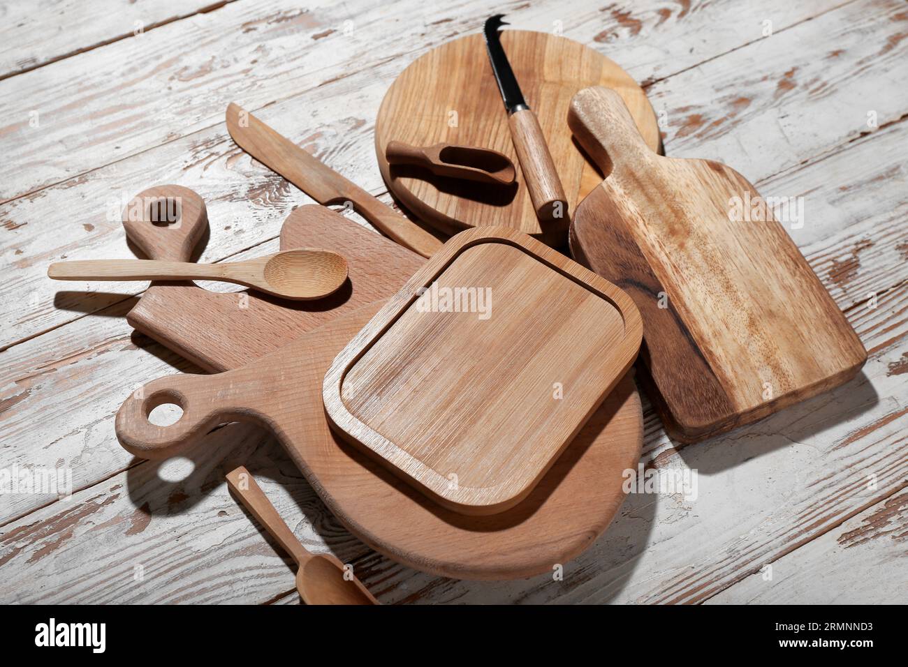 Different cutting boards with spoons and knives on light wooden ...
