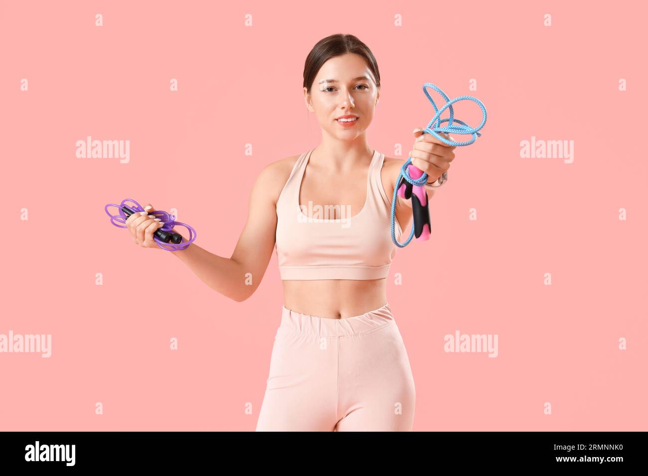 Sporty young woman with jumping ropes on pink background Stock Photo ...