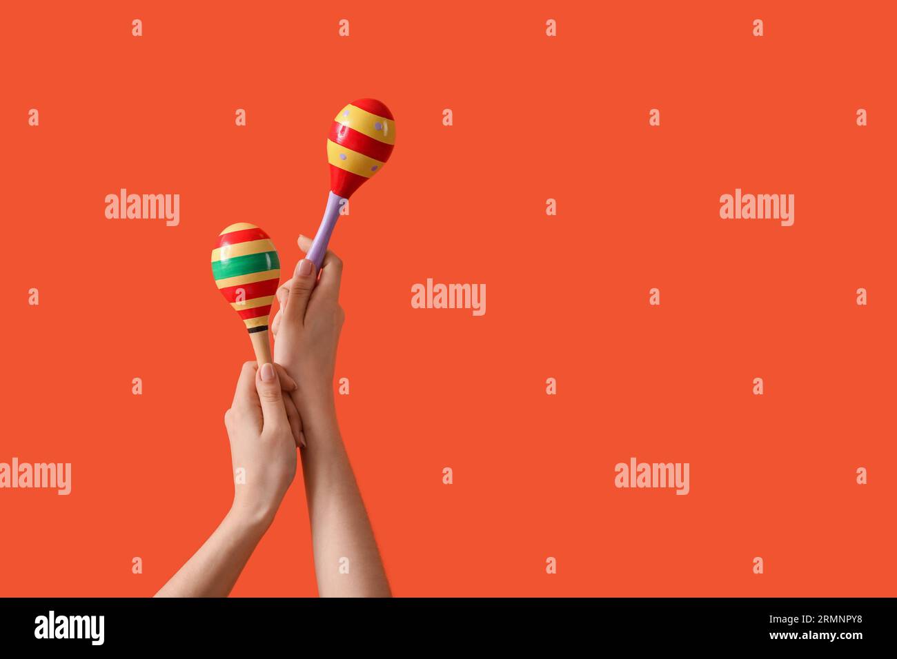 Female hands holding maracas on orange background Stock Photo - Alamy
