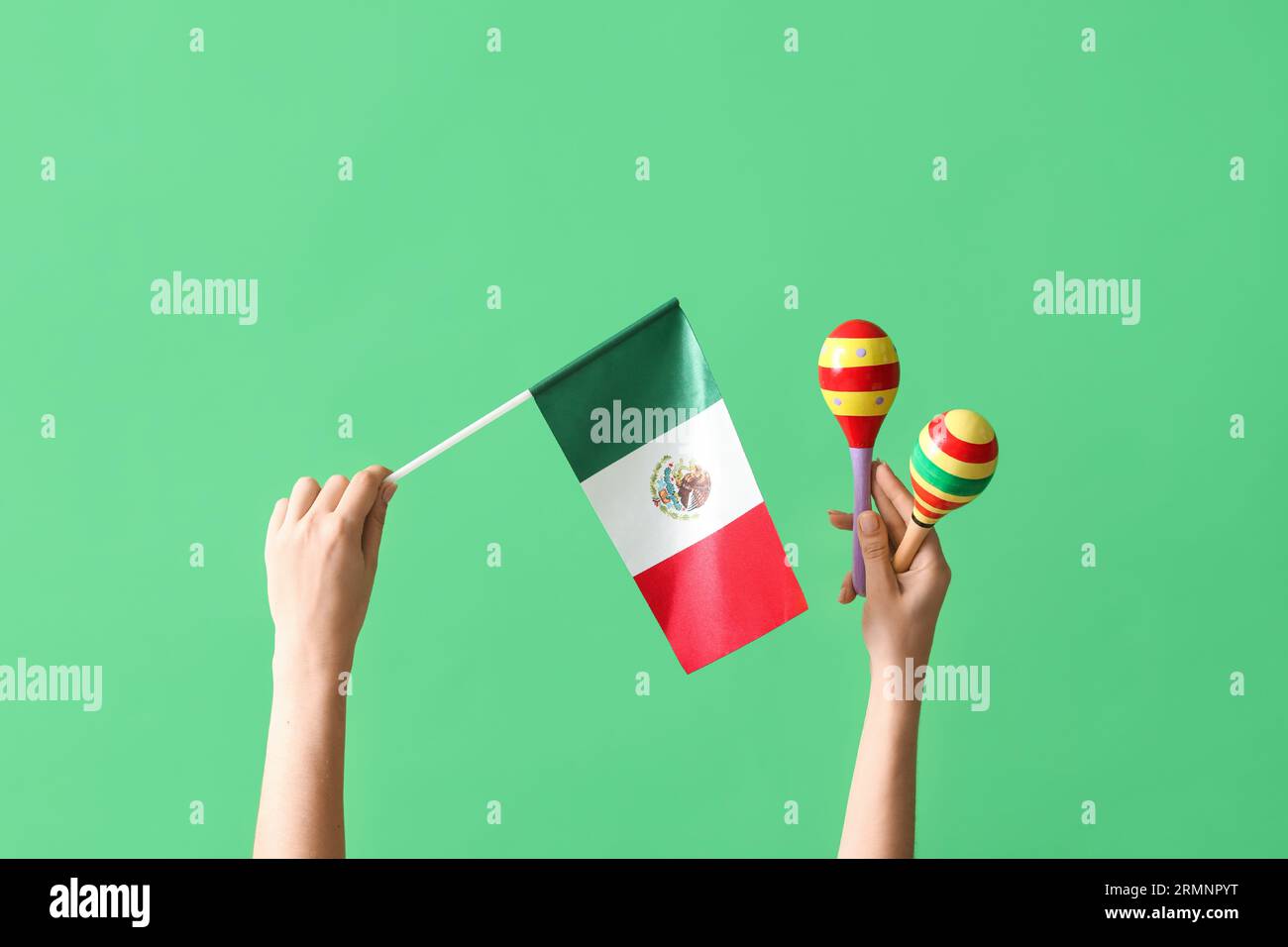 Female hands holding Mexican flag and maracas on green background Stock ...