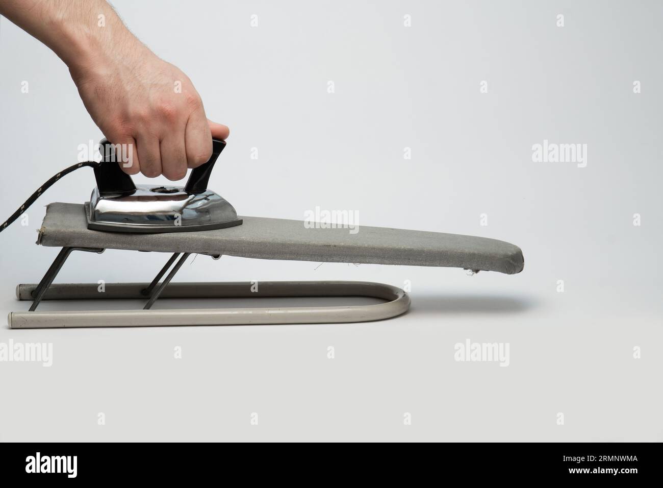 Male hand holding small old vintage electric iron on small old ironing ...
