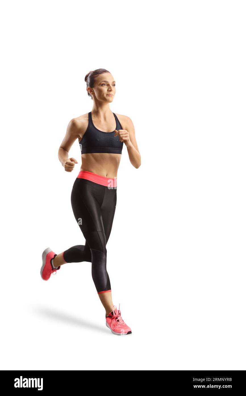 Young woman in matching leggings and crop top jogging isolated on white ...