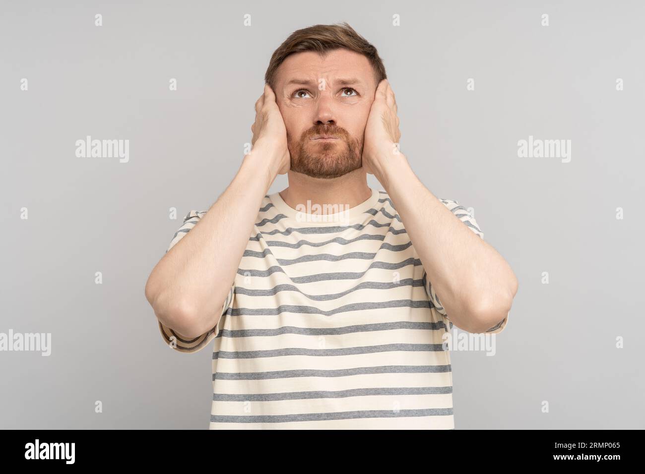 Tensed confused desperated middle aged man clutched cheeks looking up ...