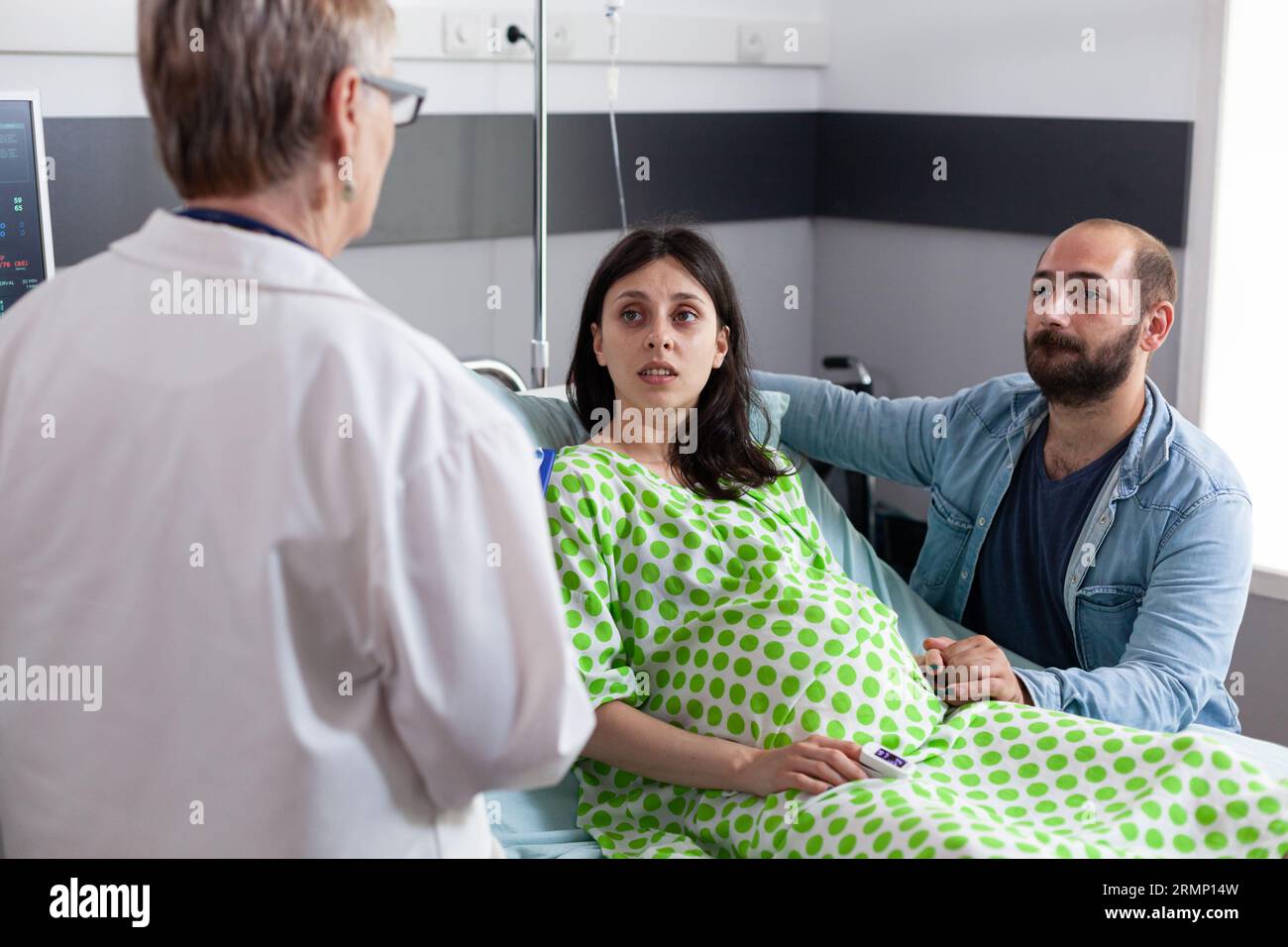 Couple discussing childbirth process with doctor in hospital ward ...