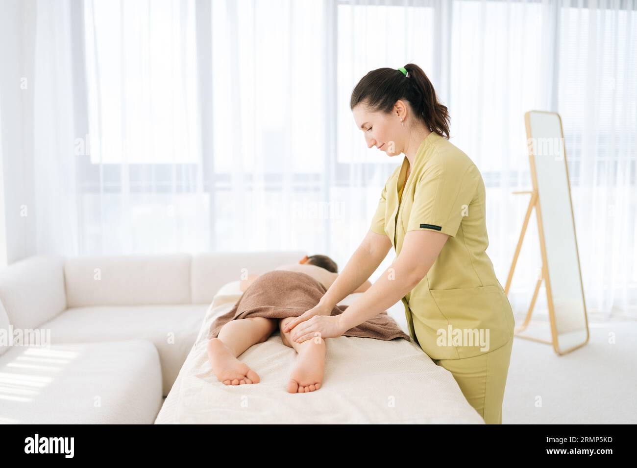 Wide shot of professional female masseuse giving therapeutic massage of ...