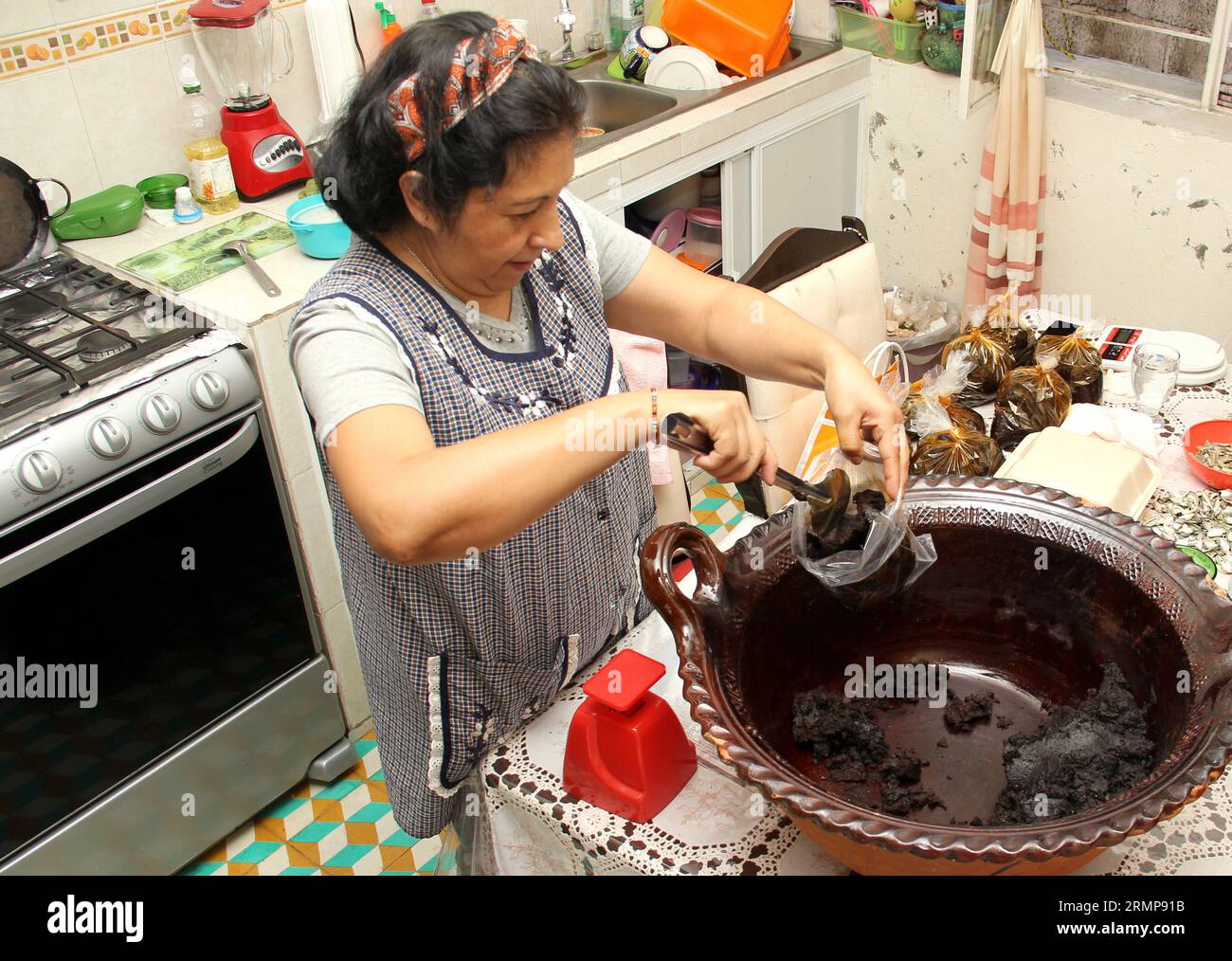 Latin Mexican adult woman prepares packages of freshly made red mole in ...