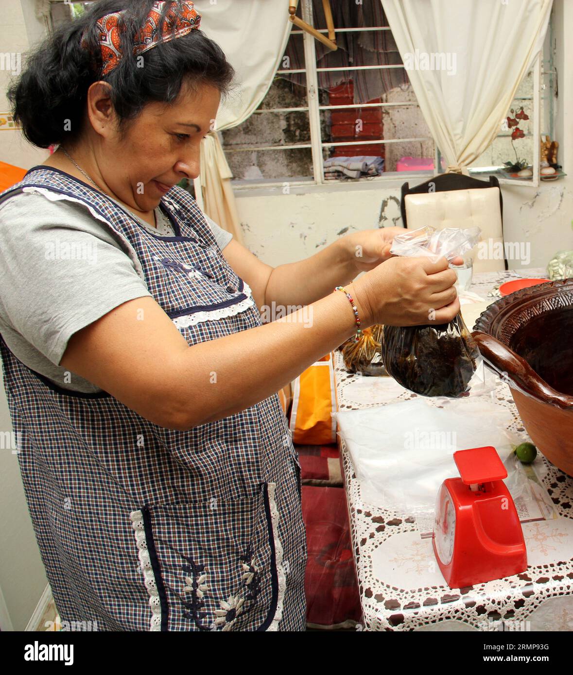 Latin Mexican adult woman prepares packages of freshly made red mole in ...