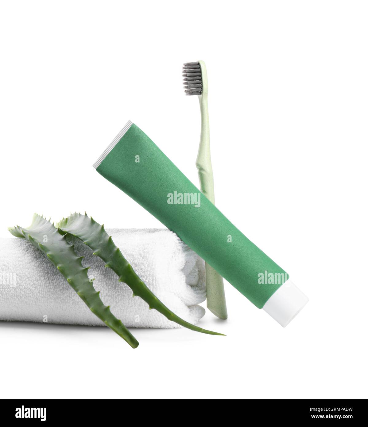Tube of toothpaste, brush, aloe vera leaves and towel on white ...