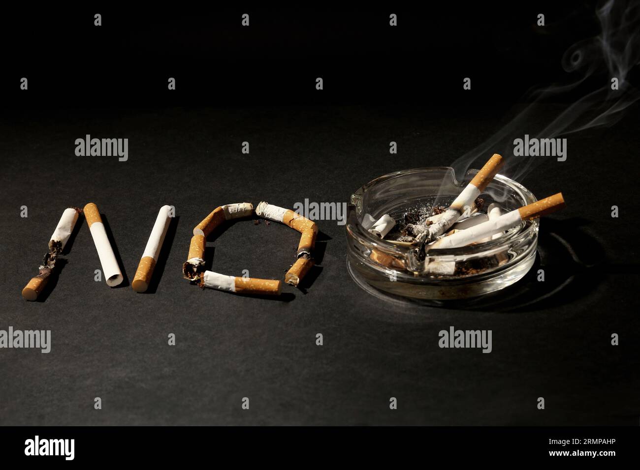 Word No made with burnt cigarettes and ashtray on black table. Stop ...