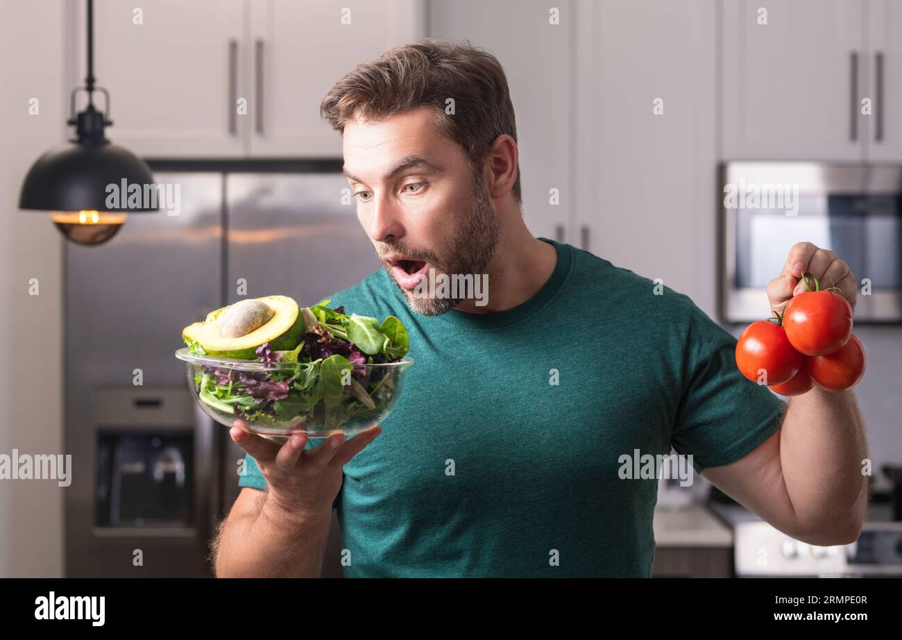 Handsome man cooking salad in kitchen. Guy cooking on kitchen with ...