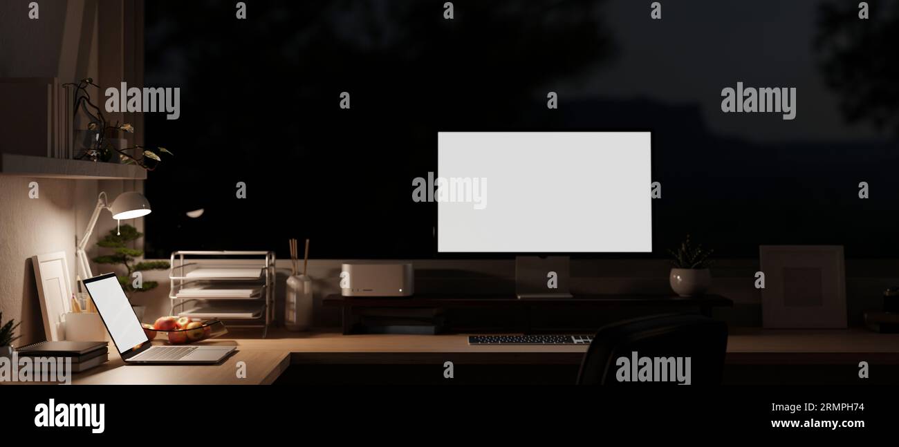 Modern office workspace at night with a computer and laptop white ...