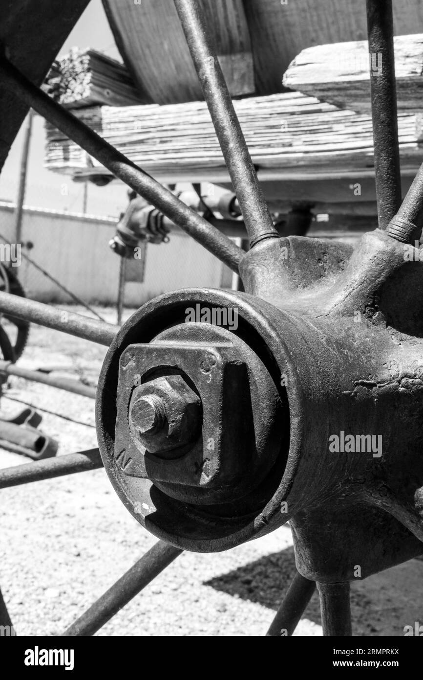A weathered wagon wheel, with rust-colored metal spokes and a center ...