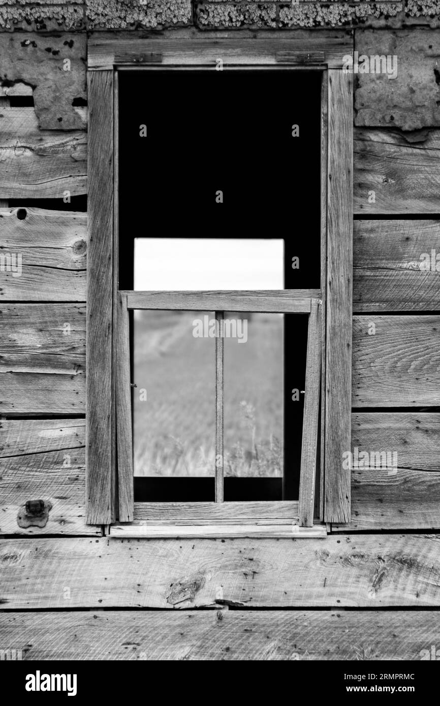 An aged, wooden barn window partially opened, letting in natural light ...
