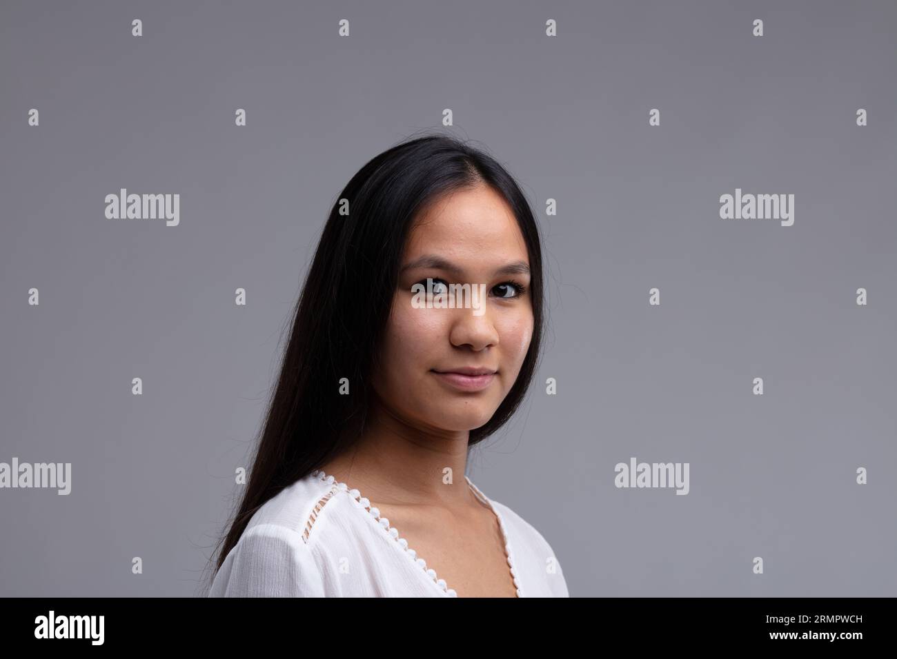 Attractive dark haired woman with a serene expression half turning to ...