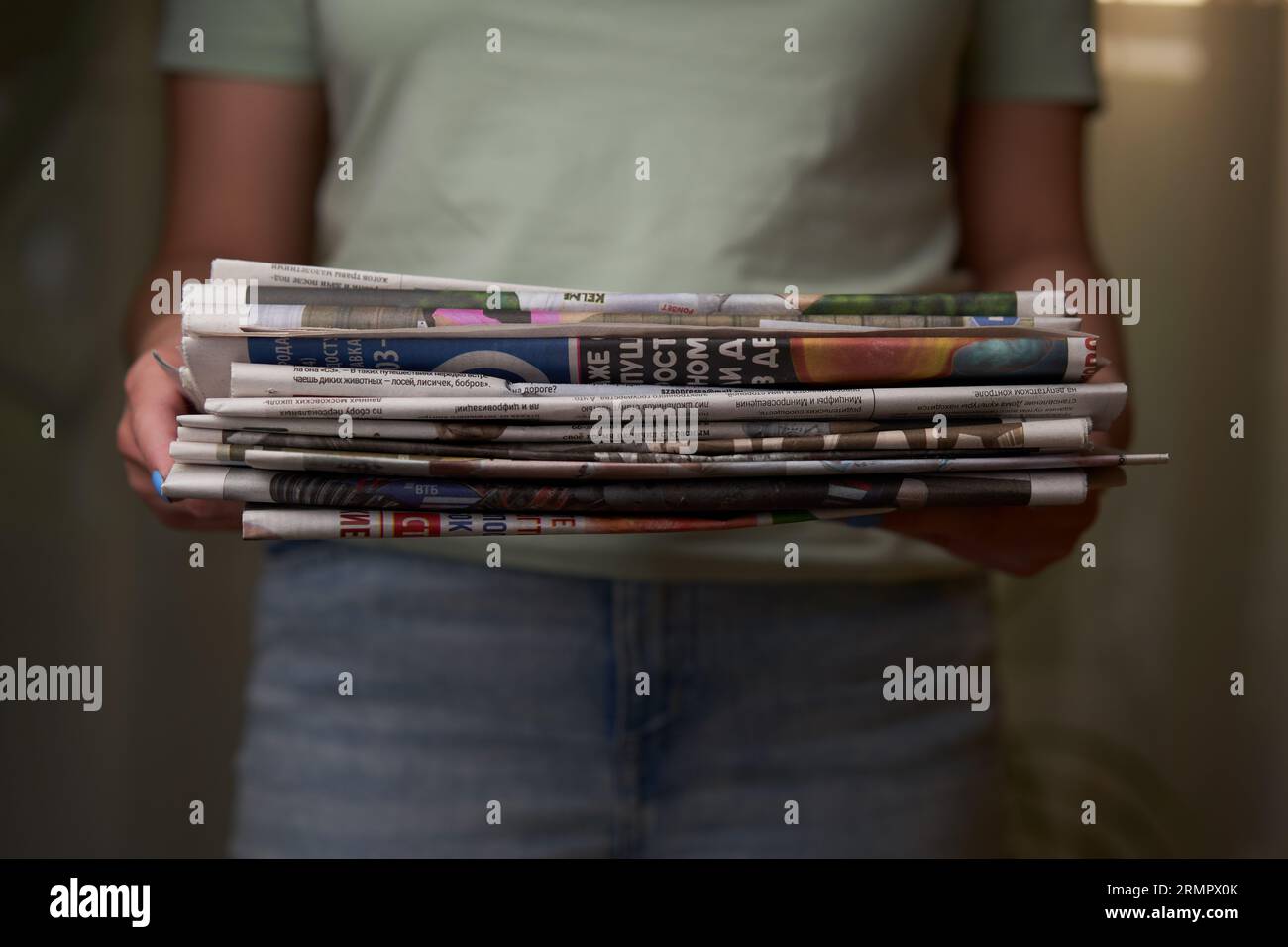 A woman stacks old newspapers in a pile, waste paper collect. Preparing ...