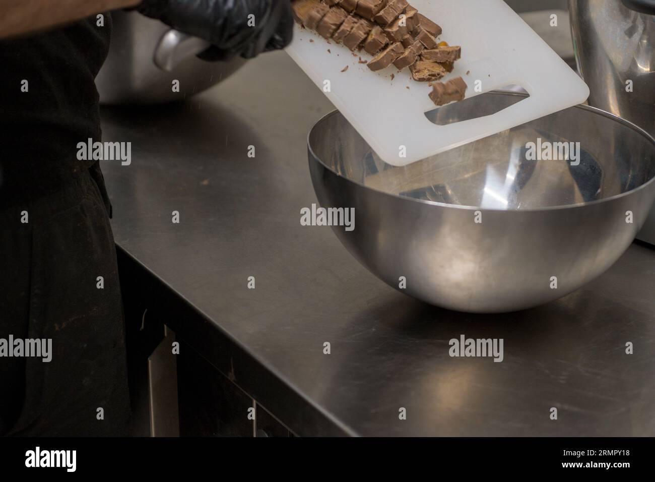 chef cutting chocolate fudge candy for cheesecake preparation close up ...