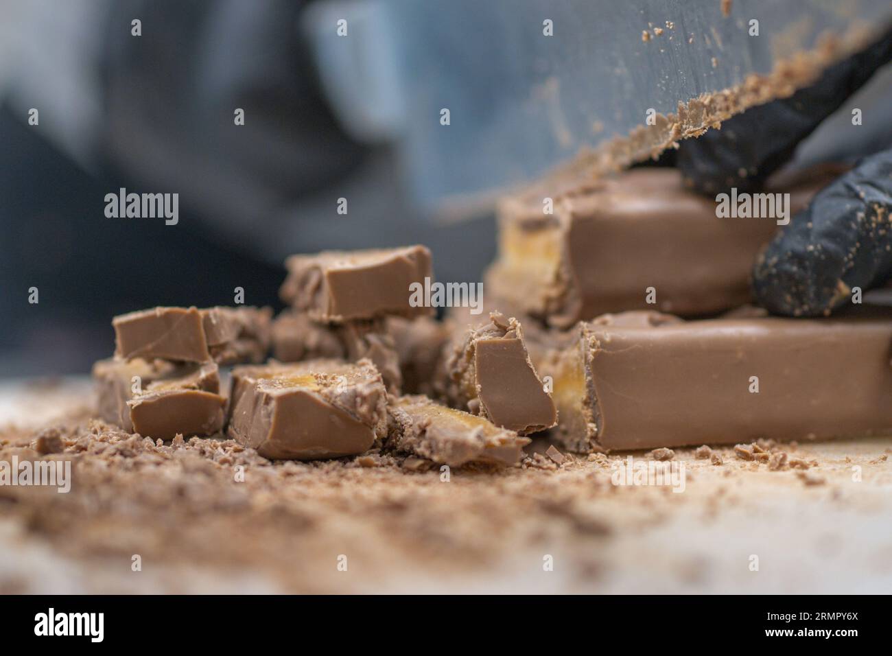 chef cutting chocolate fudge candy for cheesecake preparation close up ...