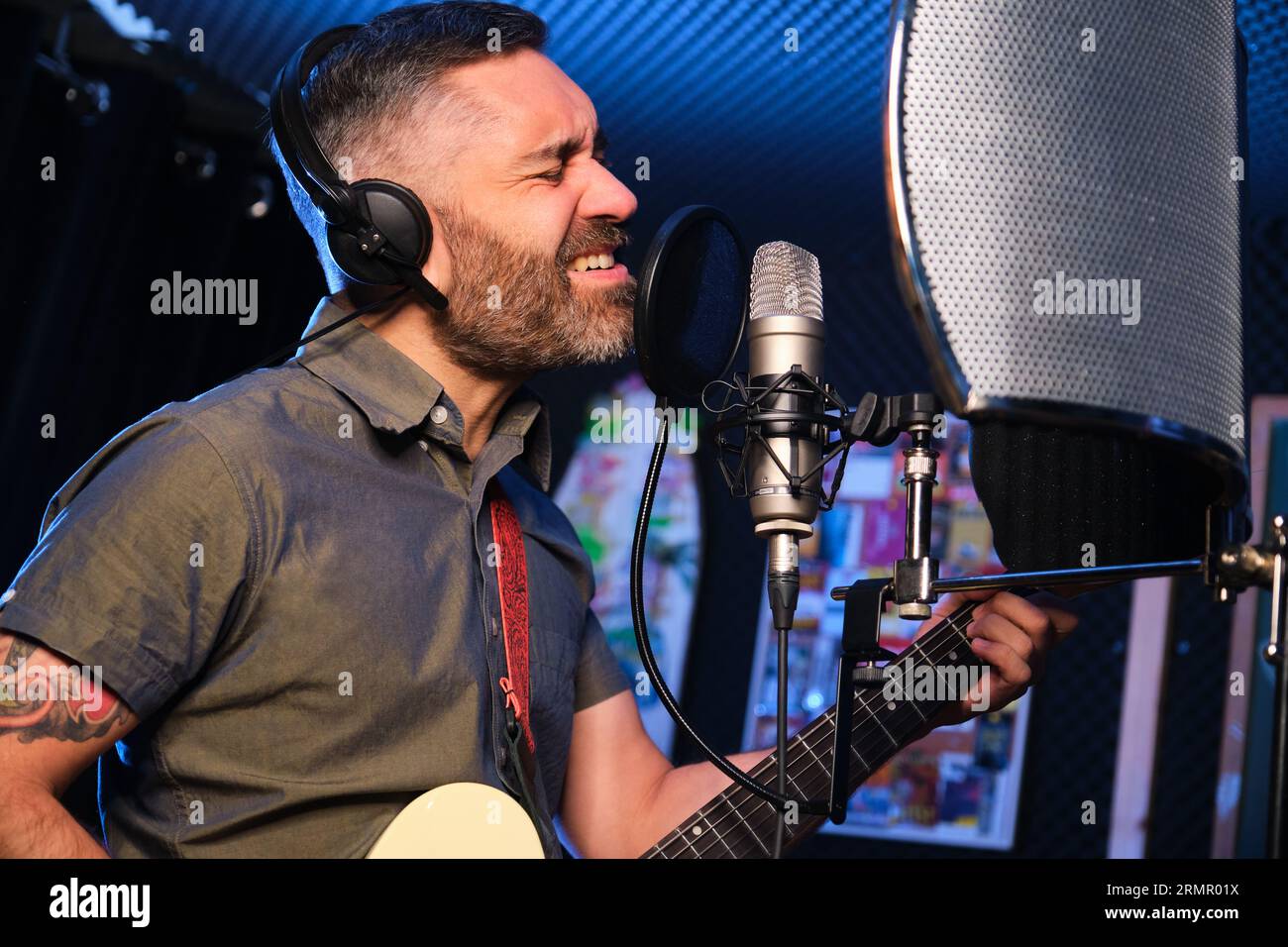 Male singer and guitarist wearing headphones performing a new single ...
