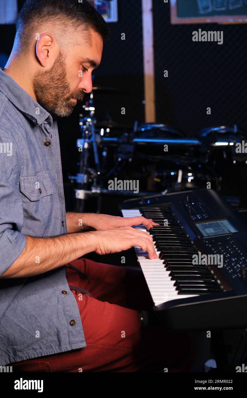 Musician man playing keyboard synthesizer piano in a recording studio ...