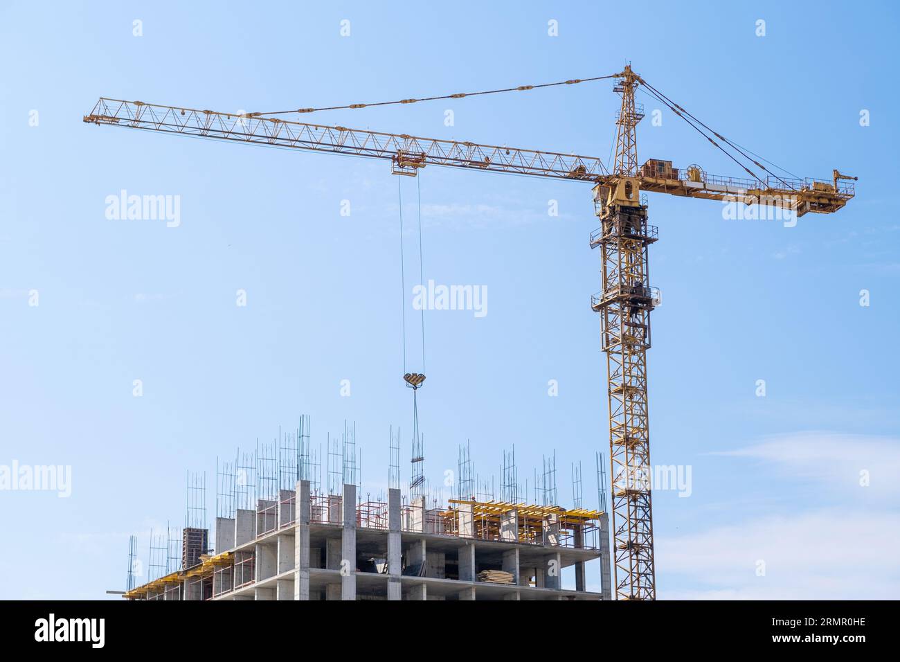 A crane and a building under construction against a blue sky background ...