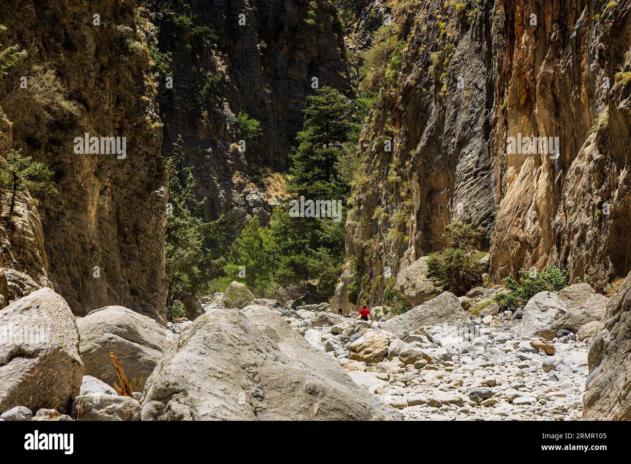 Hikers in a deep gorge surrounded by spectacular cliffs during a hot ...