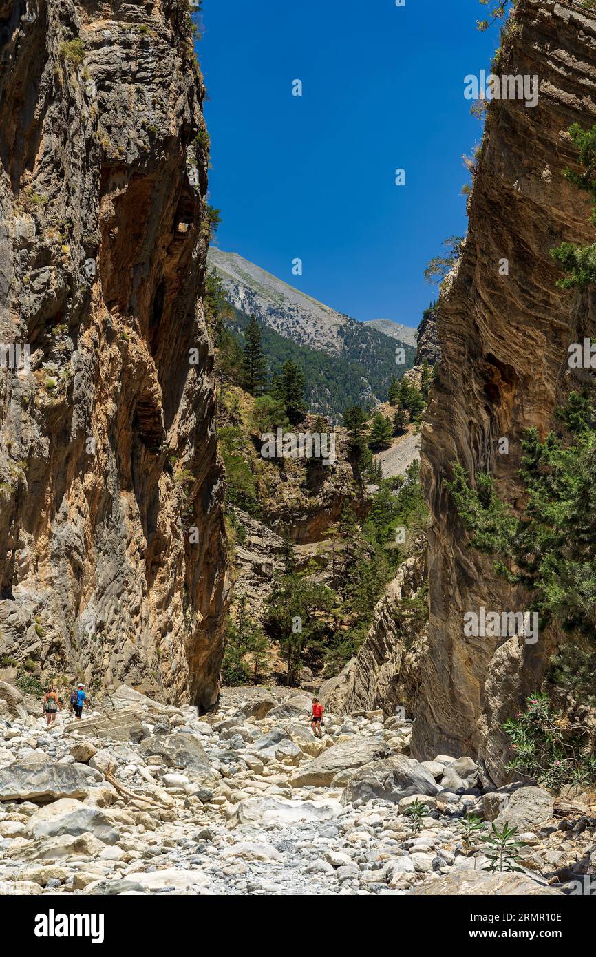 Hikers in a deep gorge surrounded by spectacular cliffs during a hot ...