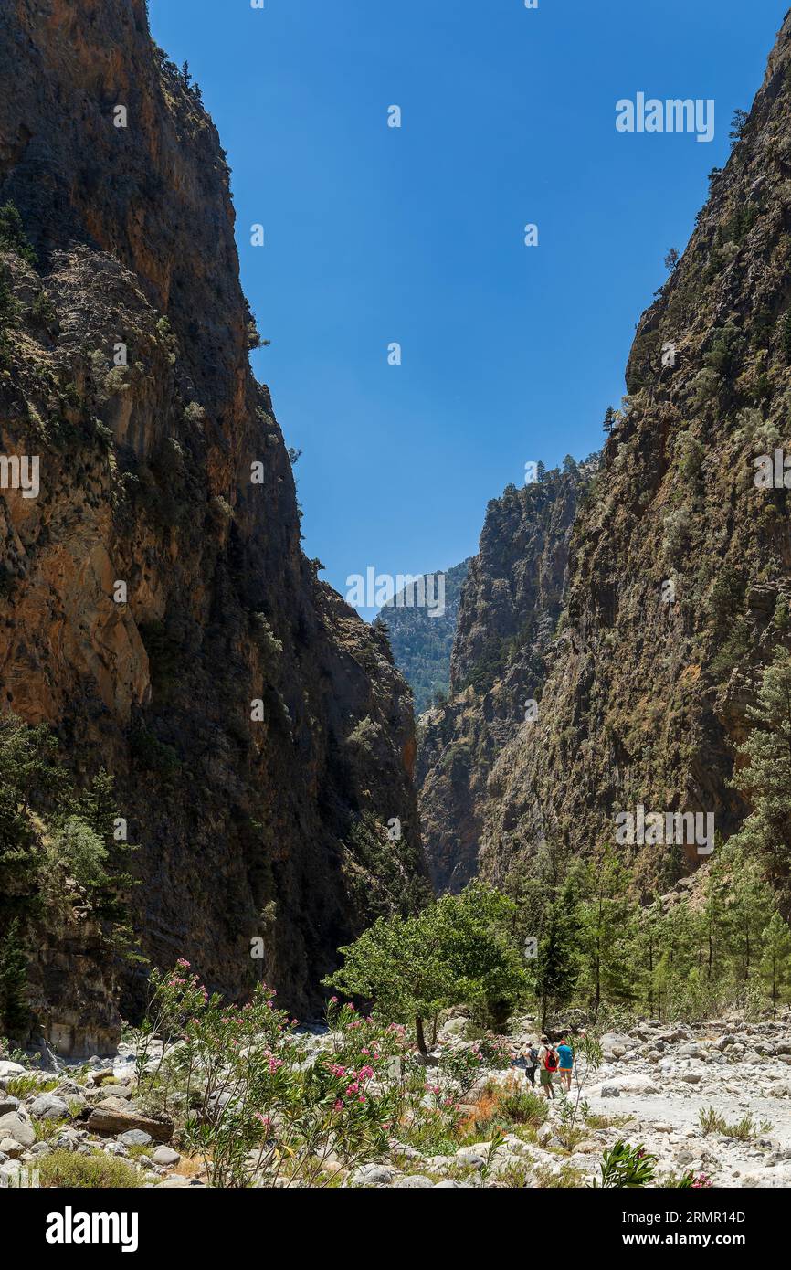 Hikers in a deep gorge surrounded by spectacular cliffs during a hot ...