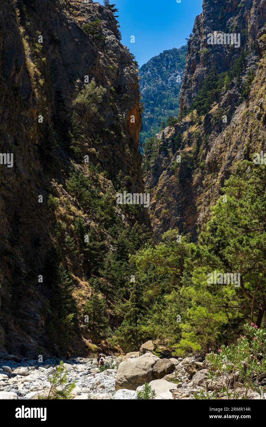 Hikers in a deep gorge surrounded by spectacular cliffs during a hot ...