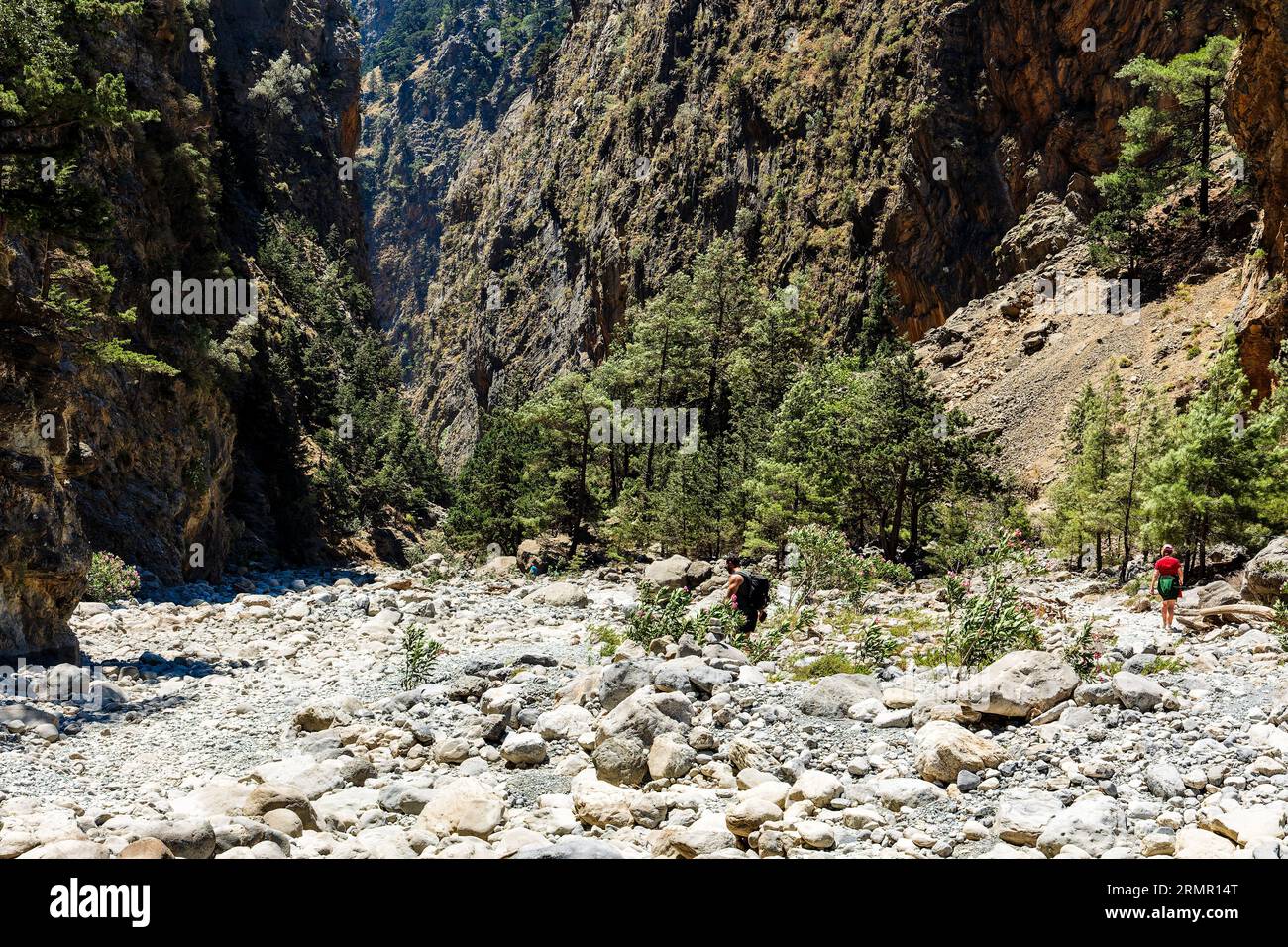 Hikers in a narrow gorge with huge, towering cliffs either side ...