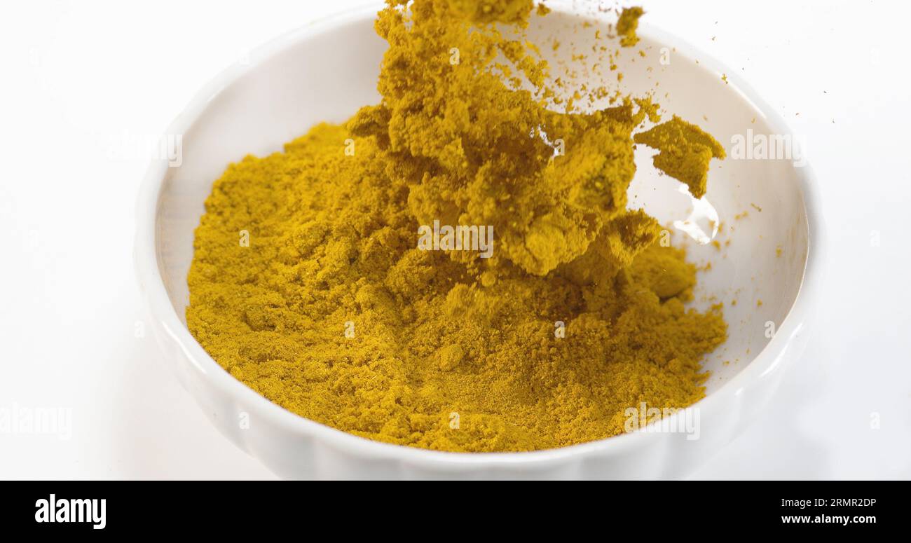 Curry Powder falling against white background Stock Photo - Alamy