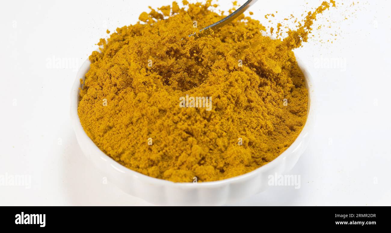 Curry Powder falling against white background Stock Photo - Alamy