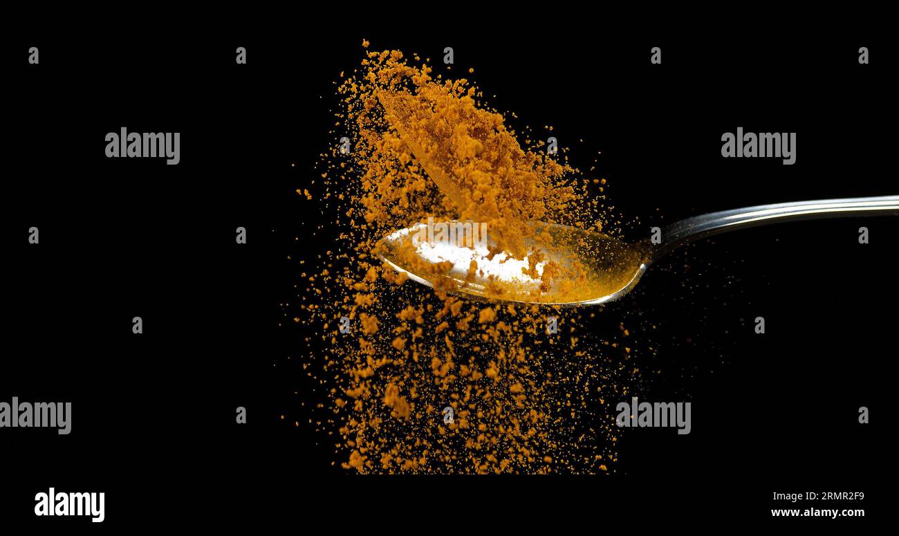 Spoon and Curry Powder falling from Spoon against Black Background ...