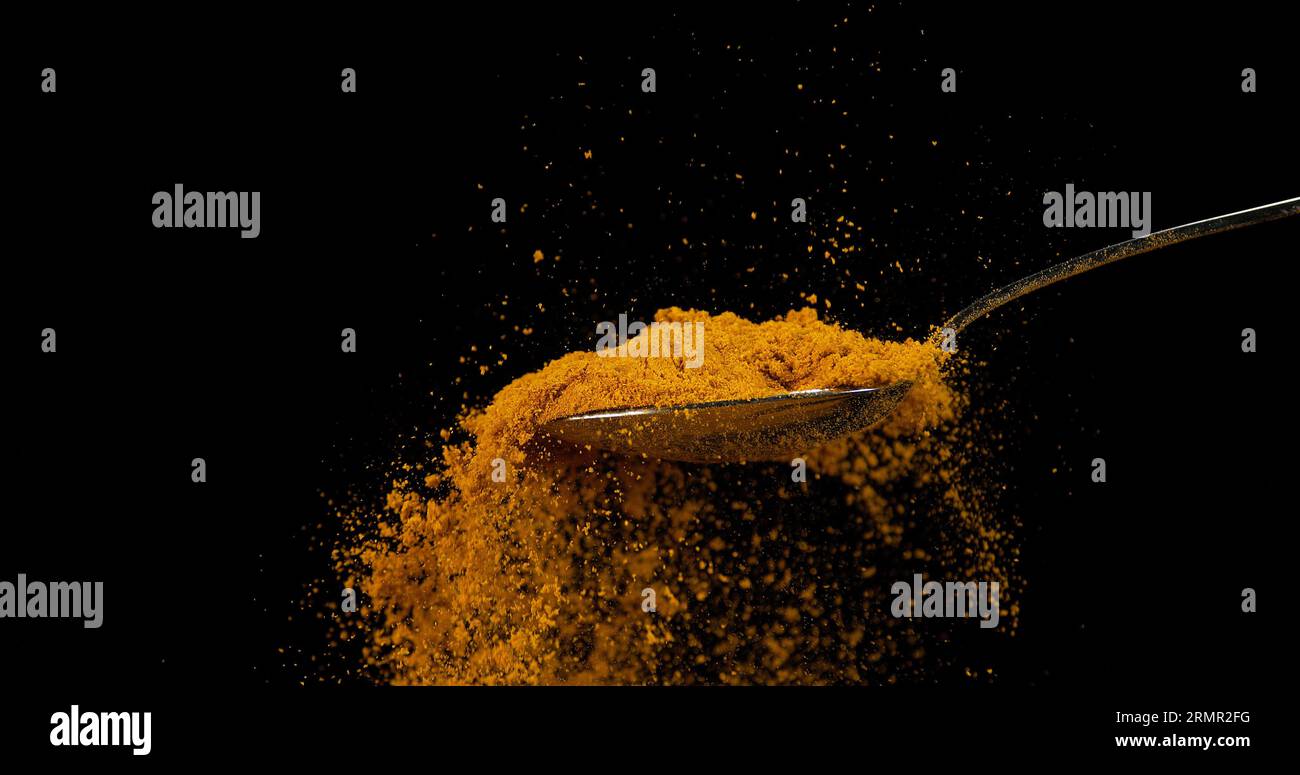 Spoon and Curry Powder falling from Spoon against Black Background ...