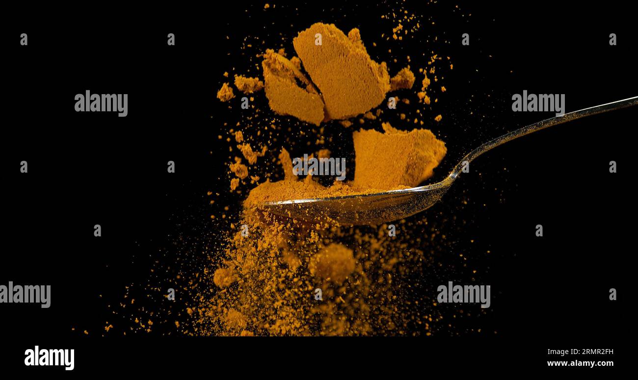 Spoon and Curry Powder falling from Spoon against Black Background ...