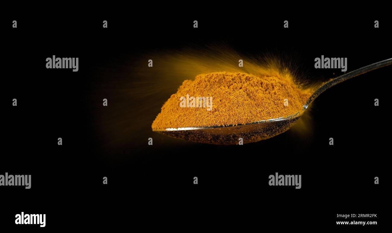Spoon and Curry Powder falling from Spoon against Black Background ...