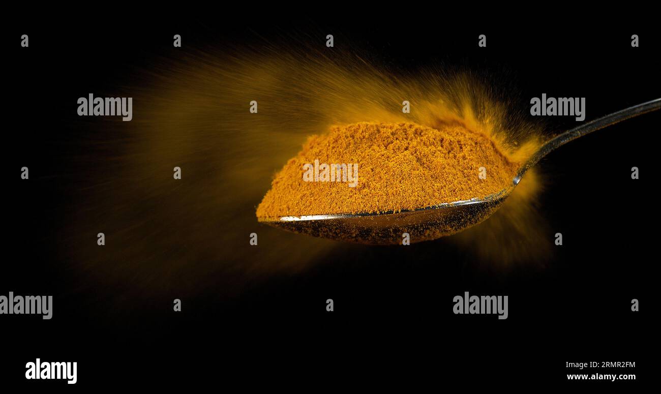 Spoon and Curry Powder falling from Spoon against Black Background ...