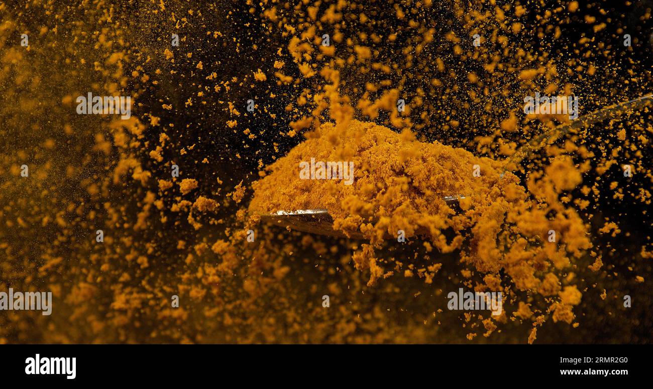 Spoon and Curry Powder falling from Spoon against Black Background ...