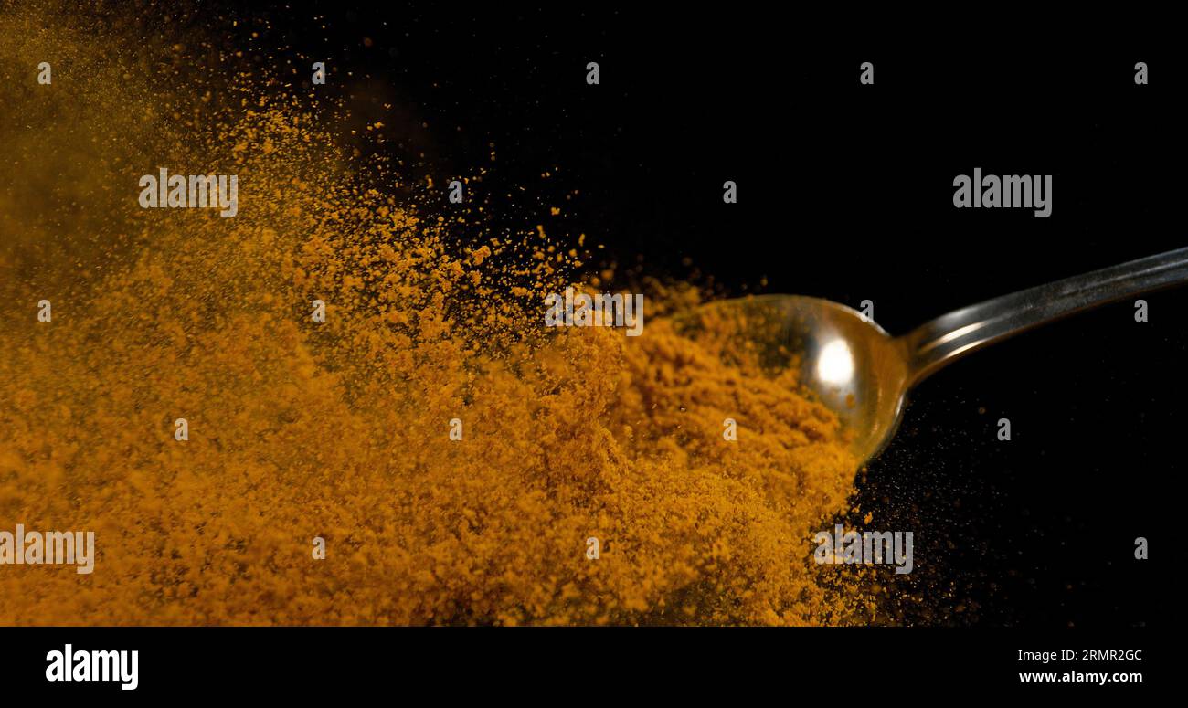 Spoon and Curry Powder falling from Spoon against Black Background ...