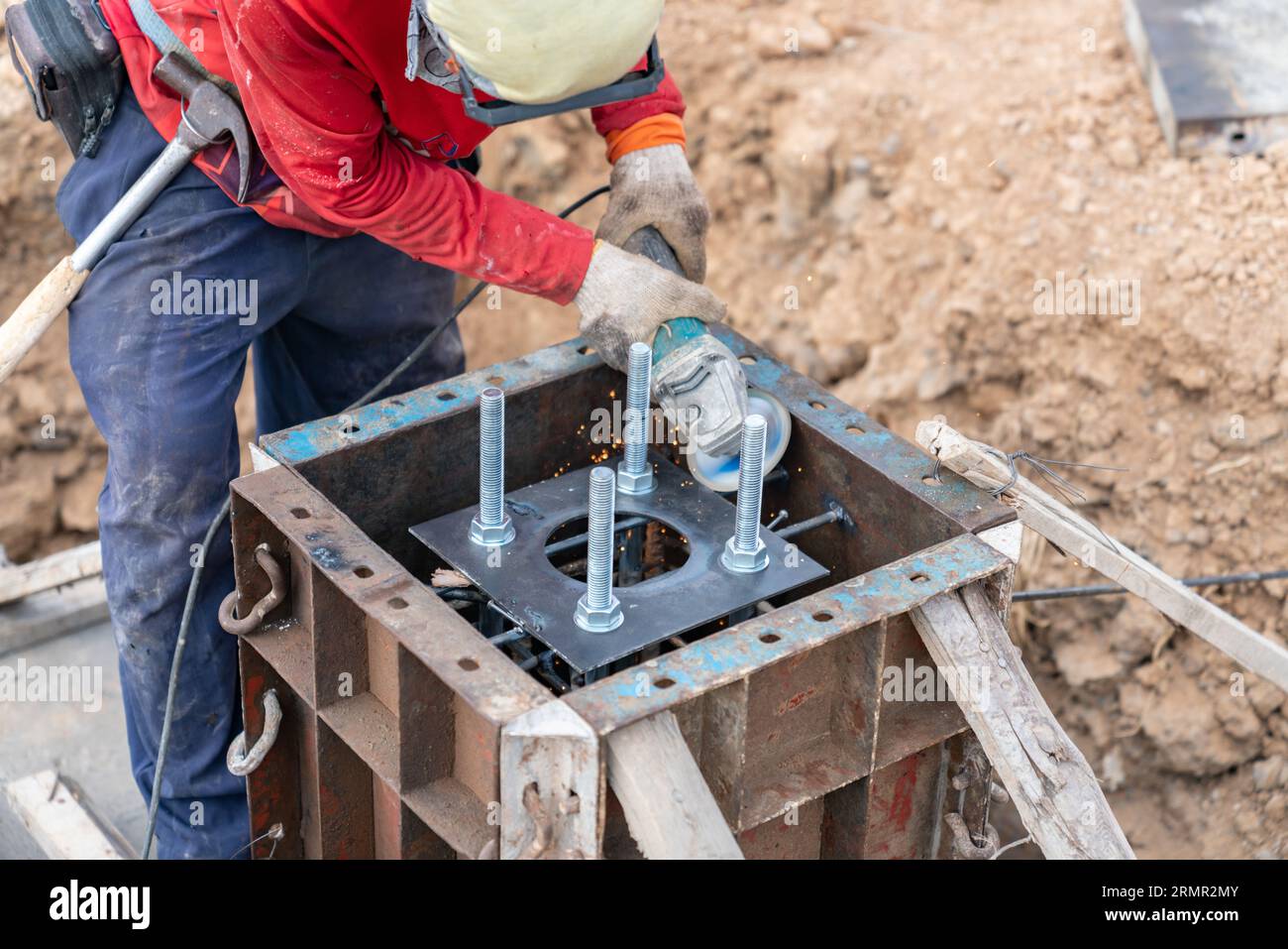 Worker using grinding machine to cut support metal plate foundation in ...