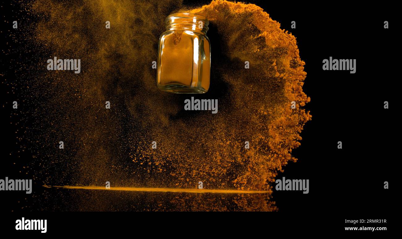 Turmeric, curcuma longa, Powder into a small jar falling against Black ...