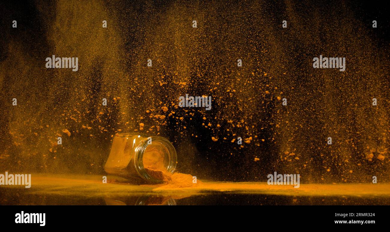 Turmeric, curcuma longa, Powder into a small jar falling against Black ...