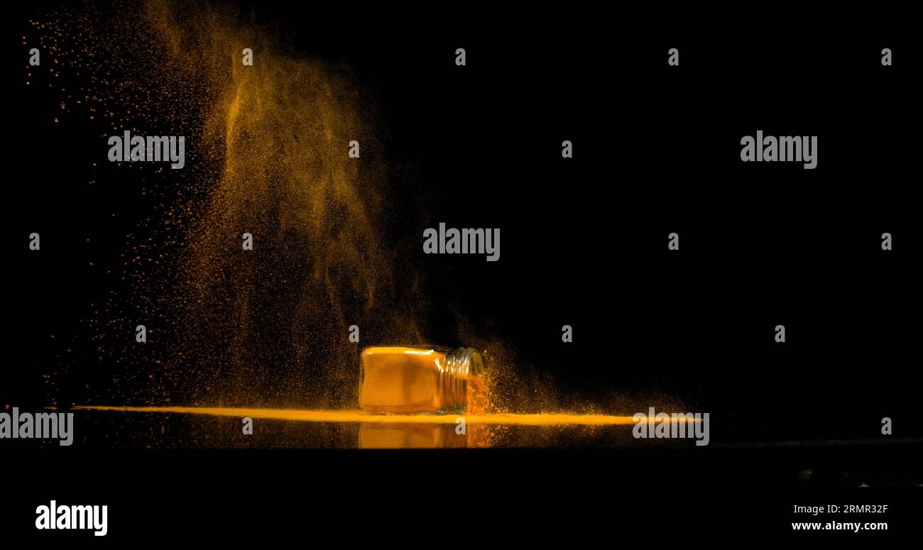 Turmeric, curcuma longa, Powder into a small jar falling against Black ...