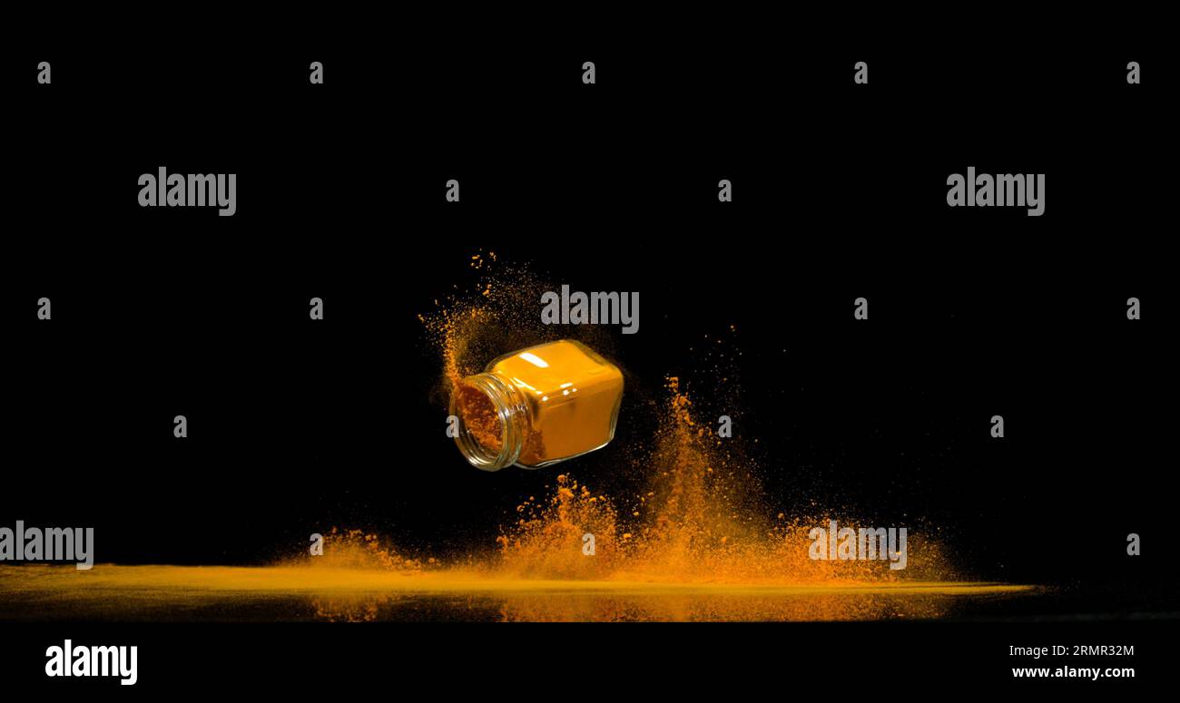Turmeric, curcuma longa, Powder into a small jar falling against Black ...