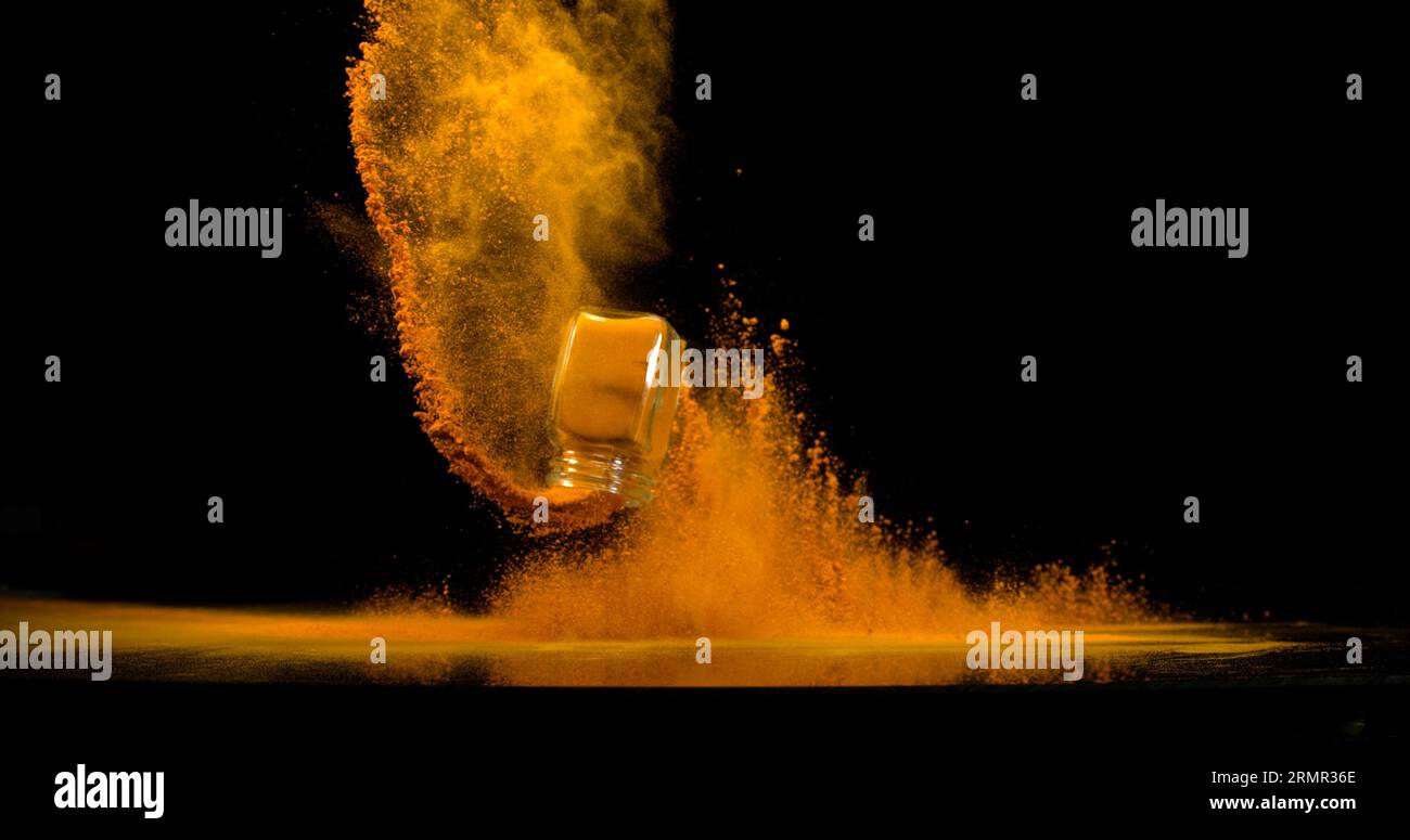 Turmeric, curcuma longa, Powder into a small jar falling against Black ...